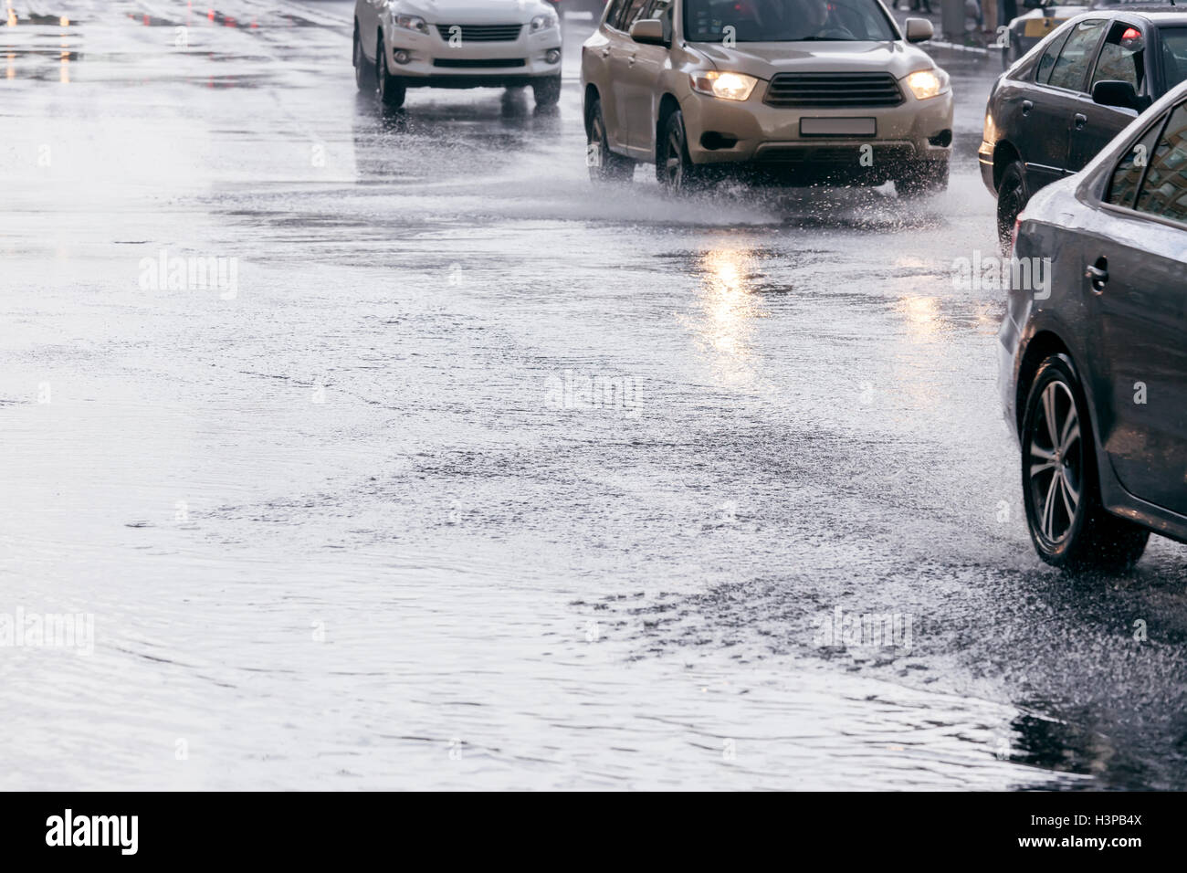 flooded street road with car traffic driving on it after heavy rain ...