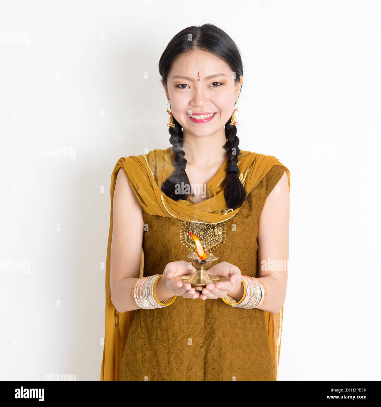 Mixed race Indian Chinese woman in traditional dress hands holding diya ...