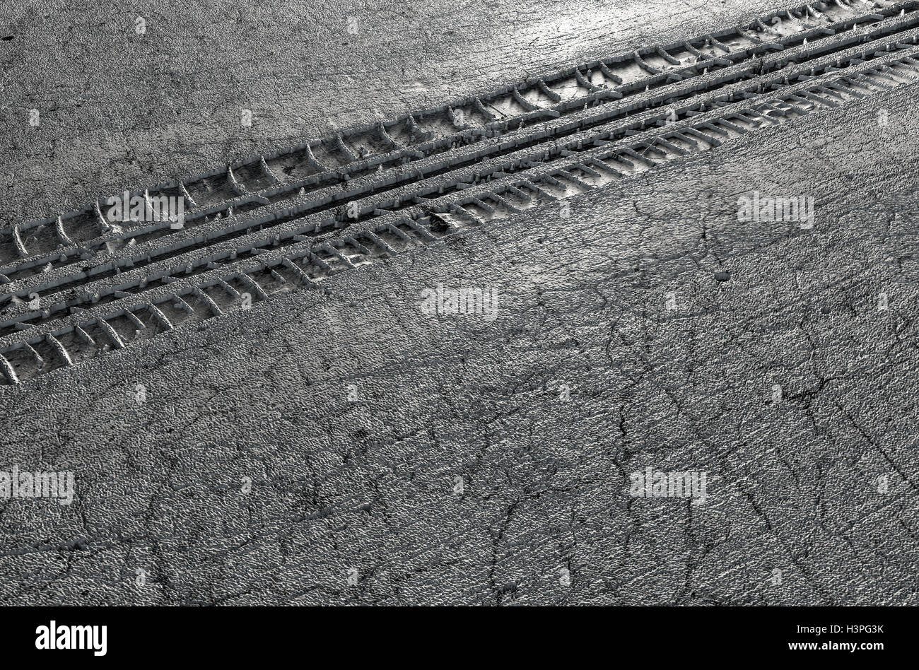 A 3D render of car tire track indenting a cracked gray surface to ...