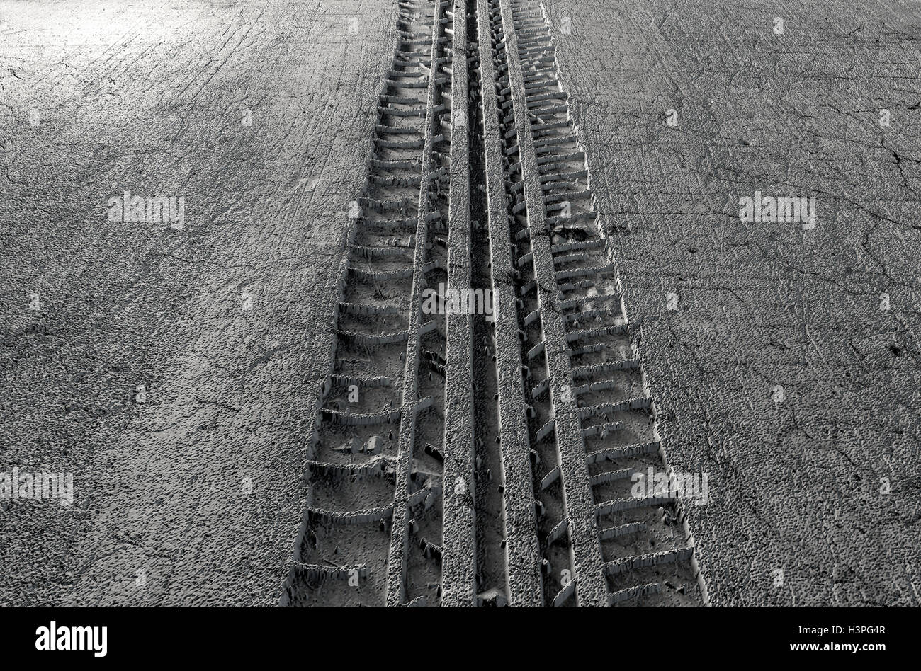 A 3D render of car tire track indenting a cracked gray surface to ...
