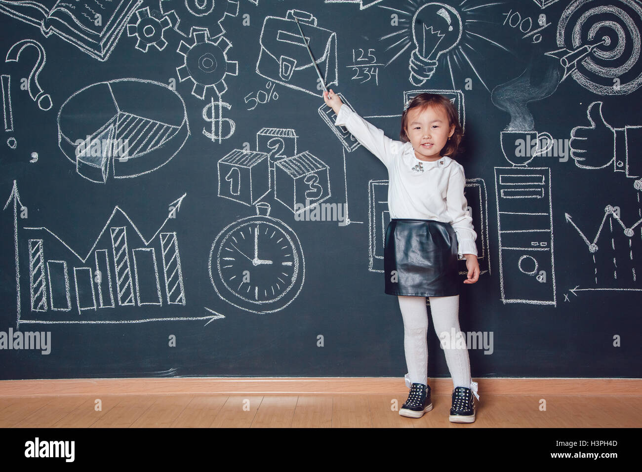 Little girl shows pointer on the wall with business or school picture ...