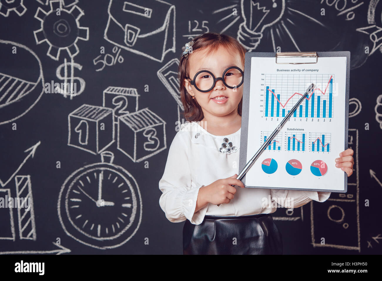 The little smart girl in glasses shows graphics company's activity on a ...