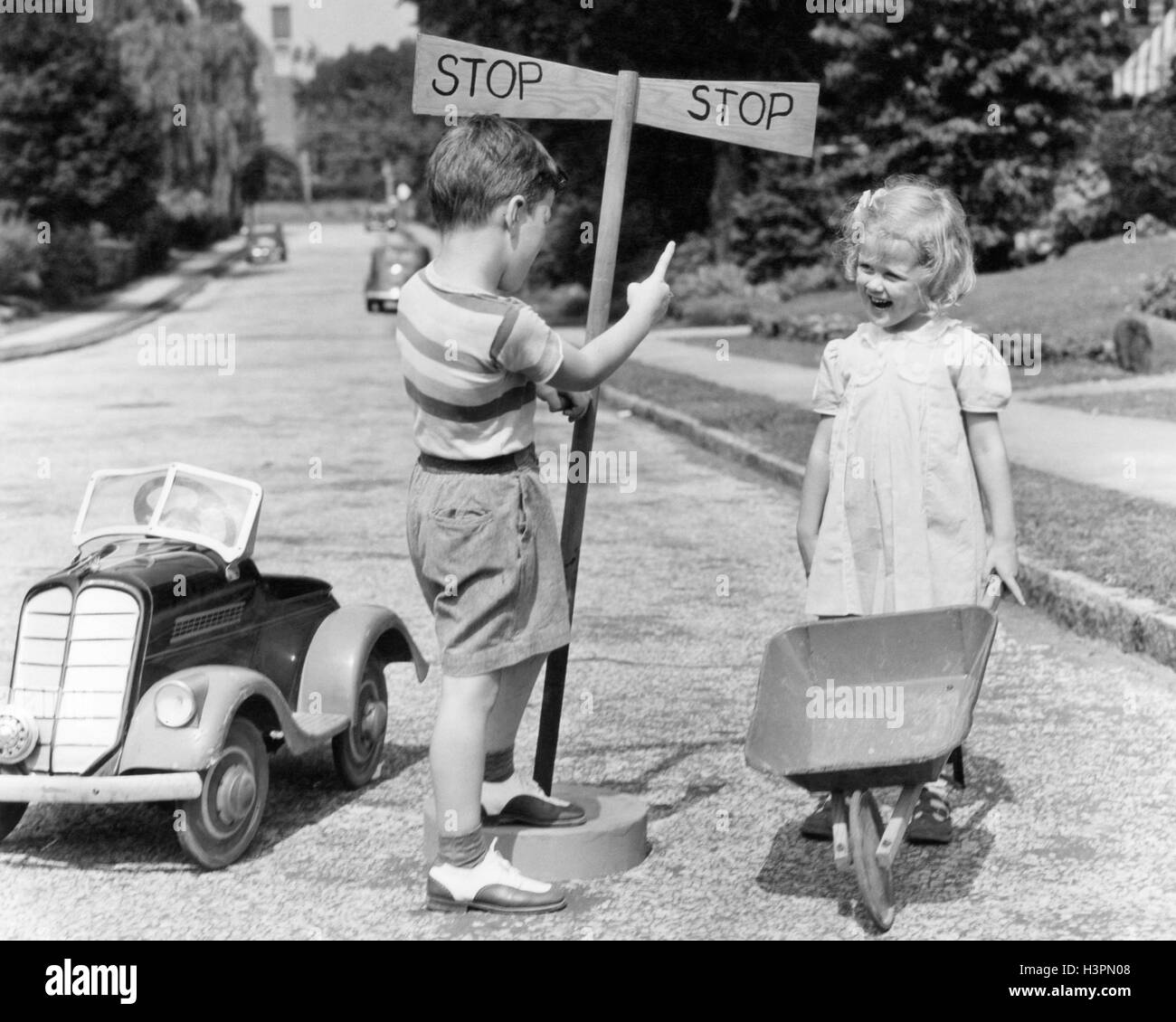 1930s 1940s BOY PLAYING TRAFFIC COP POINTING TO STOP SIGN HALTING GIRL ...