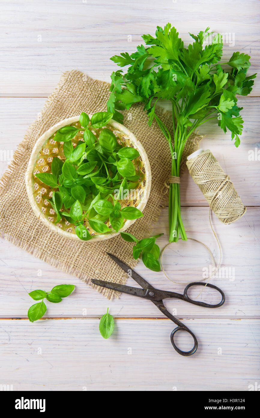 Fresh basil leaves in a basket and a bunch of parsley with an old ...