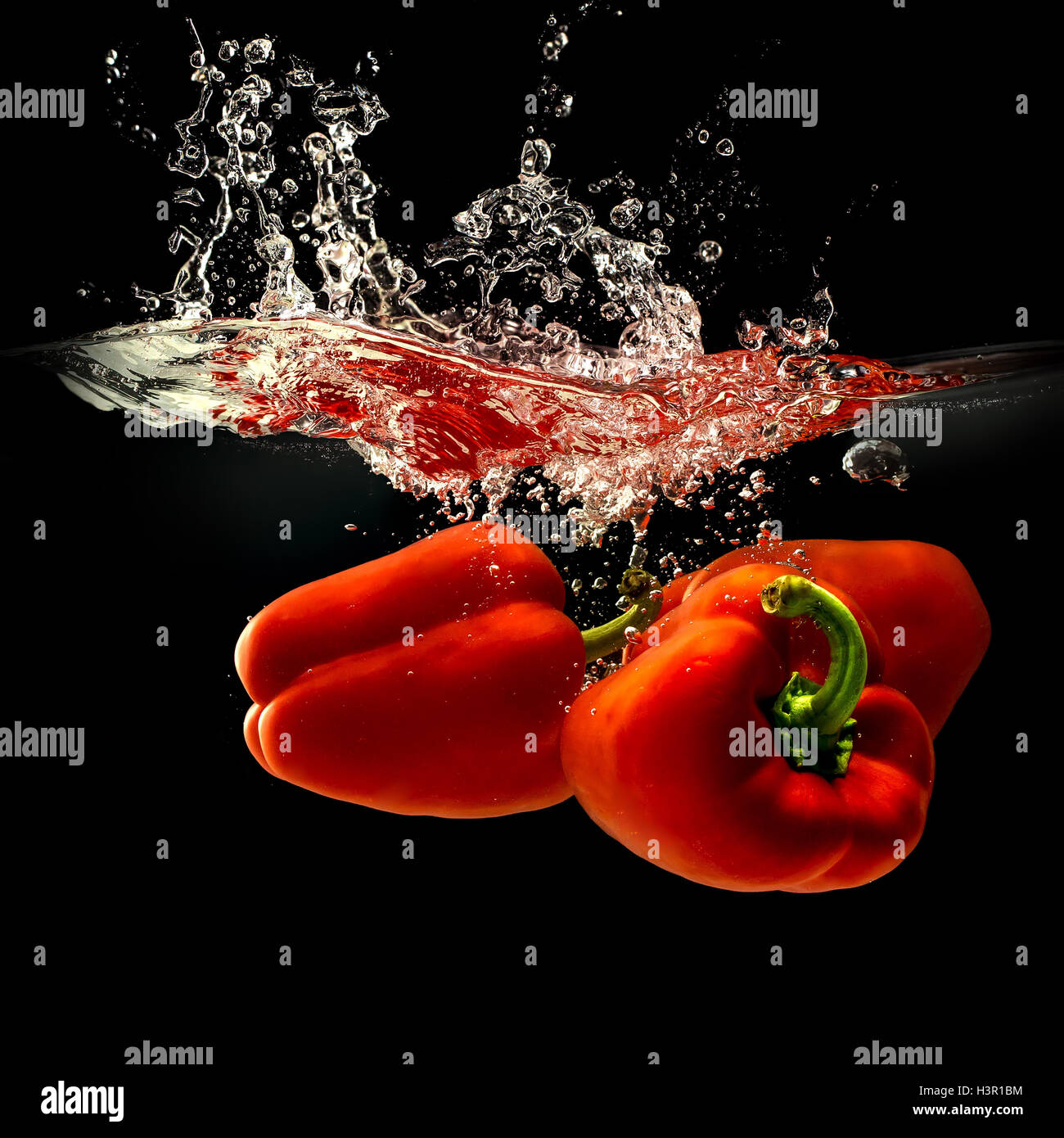 Group of bell pepper falling in water on black Stock Photo - Alamy