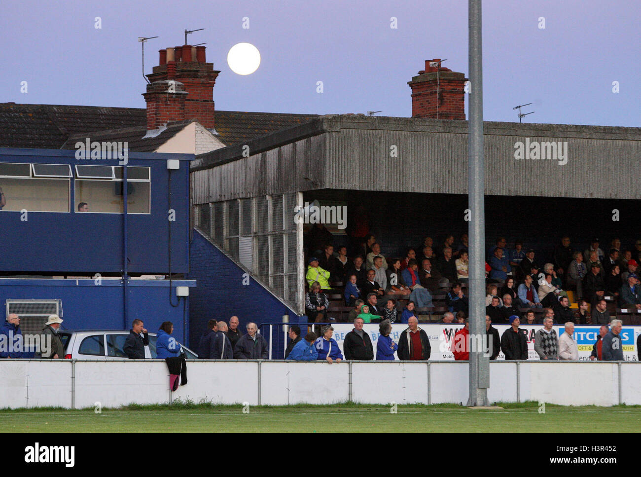 The moon rises over the main stand at Crown Meadow - Lowestoft Town vs ...