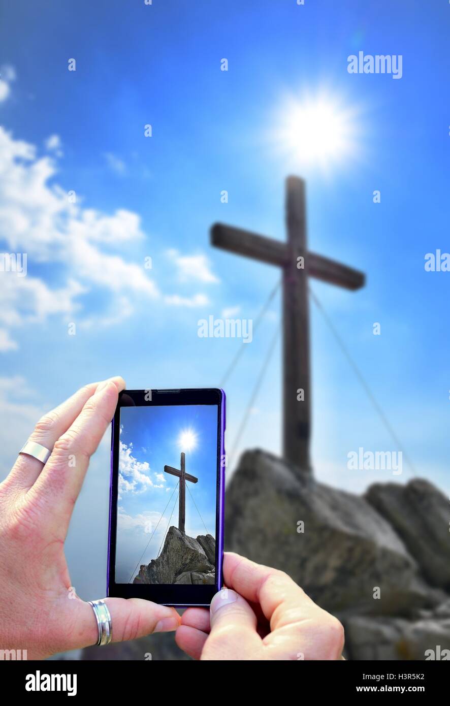 Photographing and taking photo of wooden cross on peak by smart phone ...