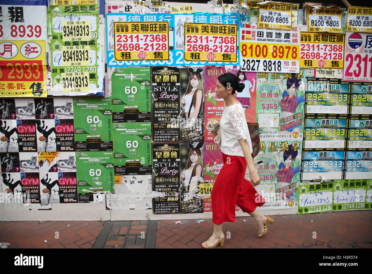 Woman walking past a road side advertisement in the Hong Kong city ...
