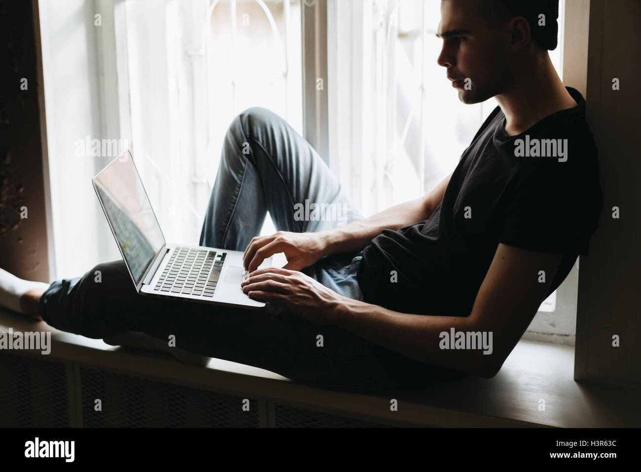 Young man typing something on a laptop Stock Photo - Alamy