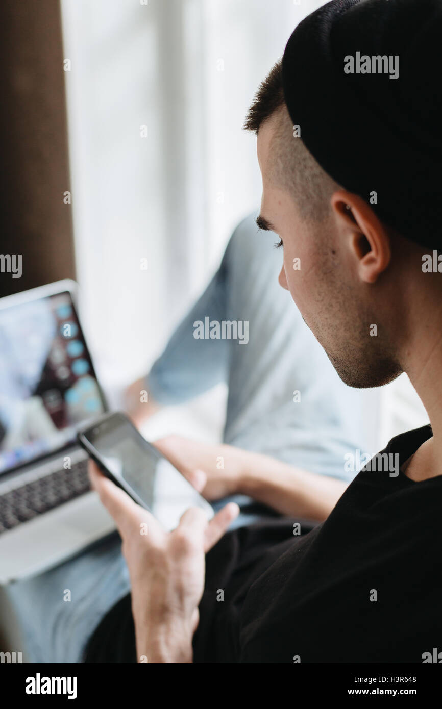 Rear view of man using cellphone and laptop Stock Photo - Alamy