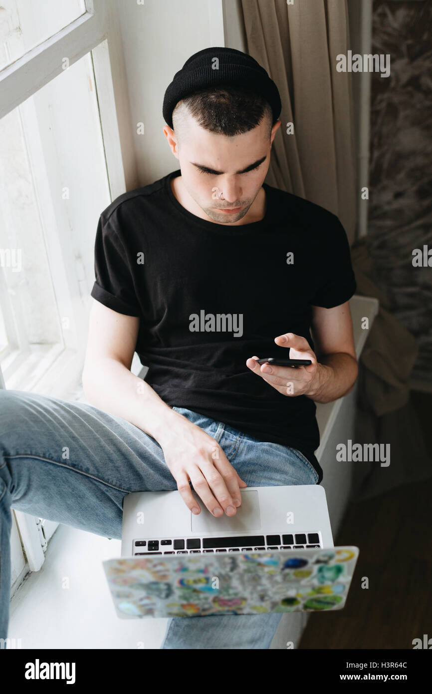 Man in black hat using laptop Stock Photo - Alamy