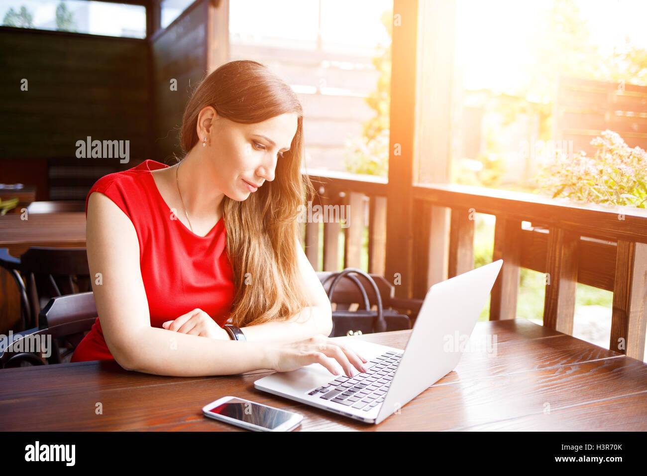 Young lady in red dress browsing the internet at the cafe. Pretty woman ...