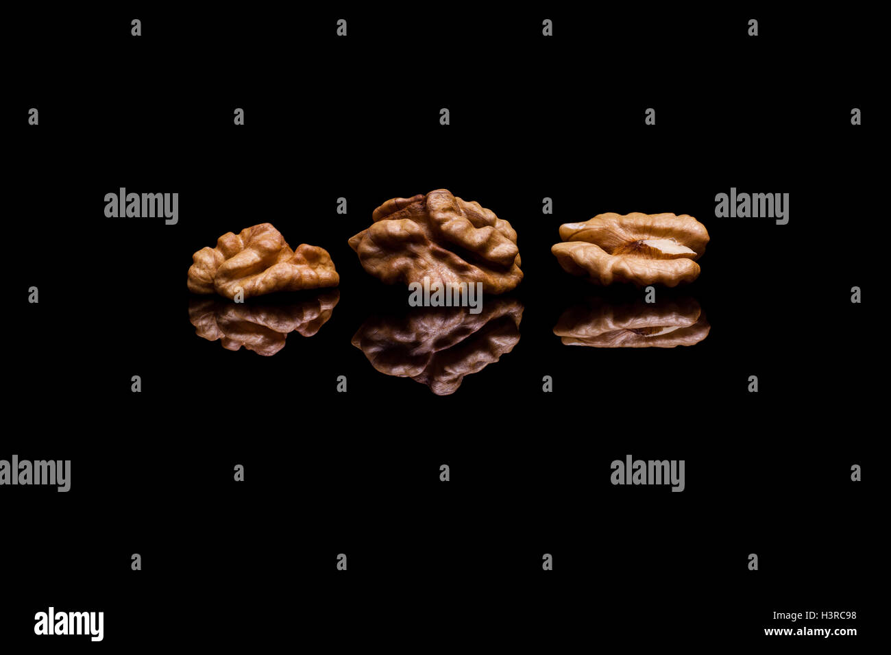 Three walnuts isolated on black reflective background Stock Photo - Alamy