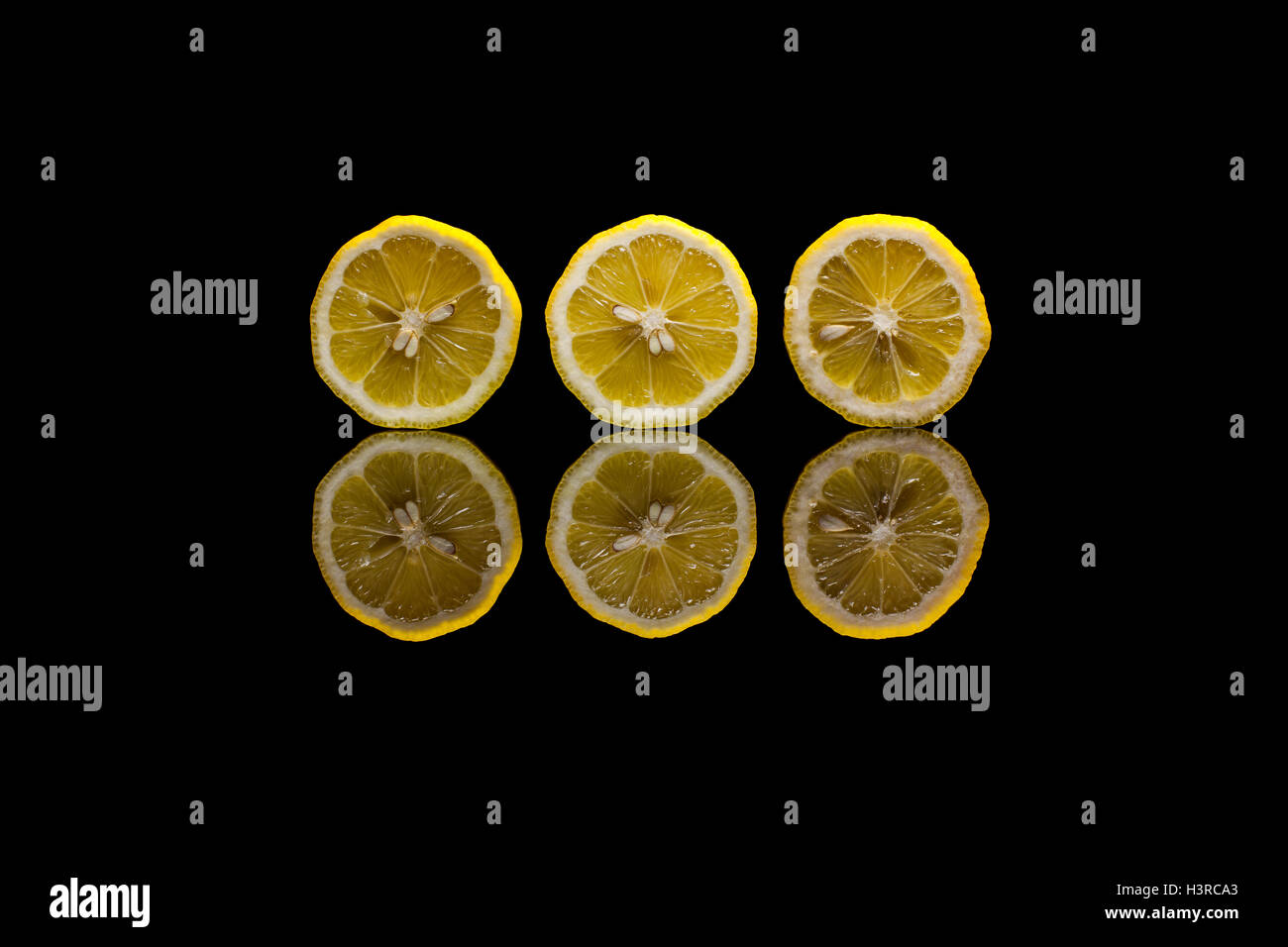 Three cut lemons isolated on black reflective background Stock Photo ...