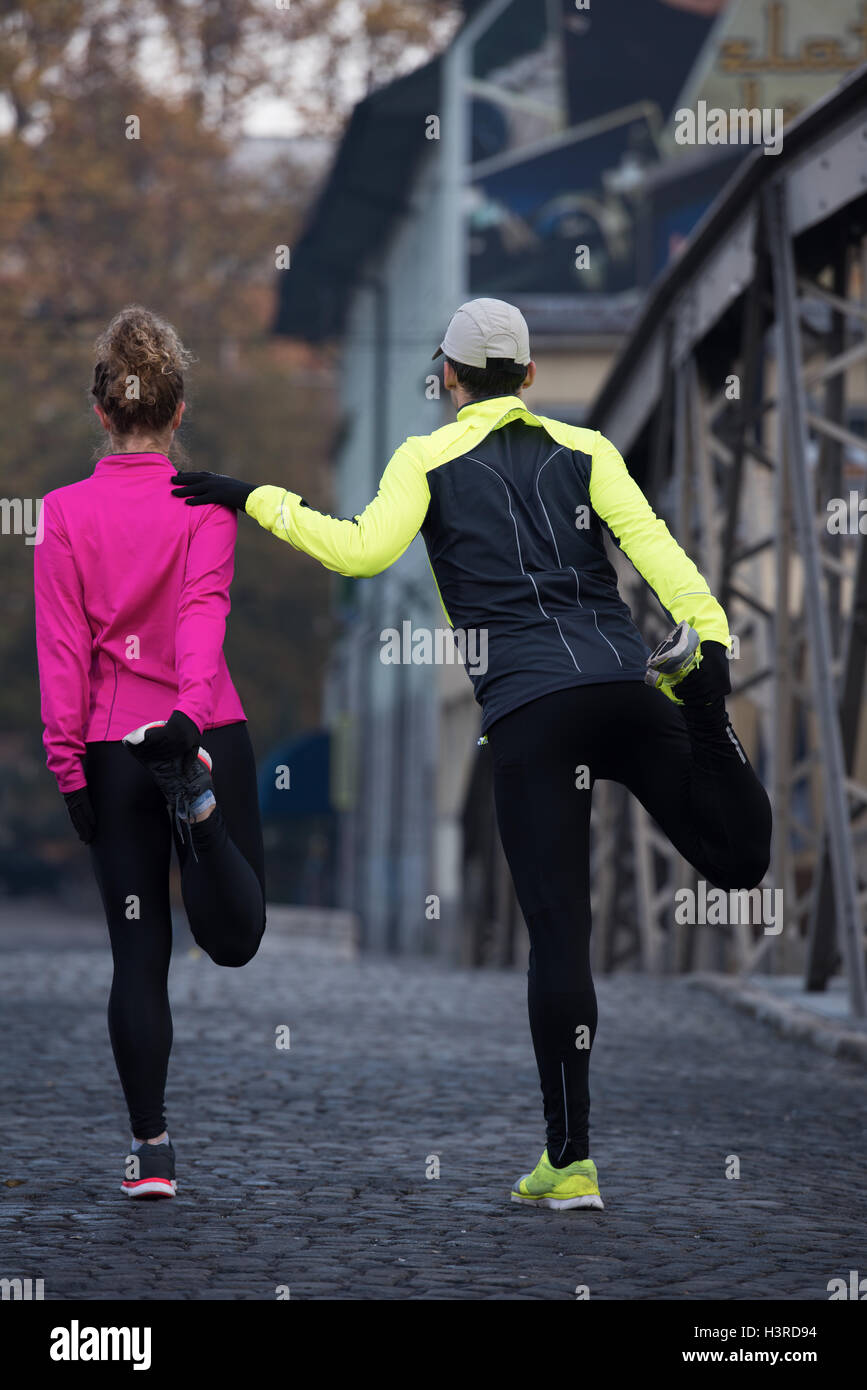 jogging couple warming up and stretching before morning running in the ...