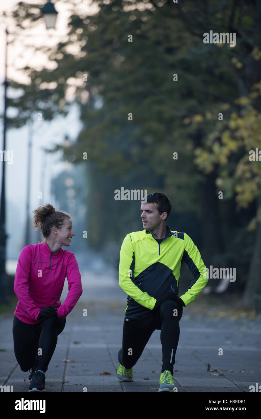 jogging couple warming up and stretching before morning running in the ...