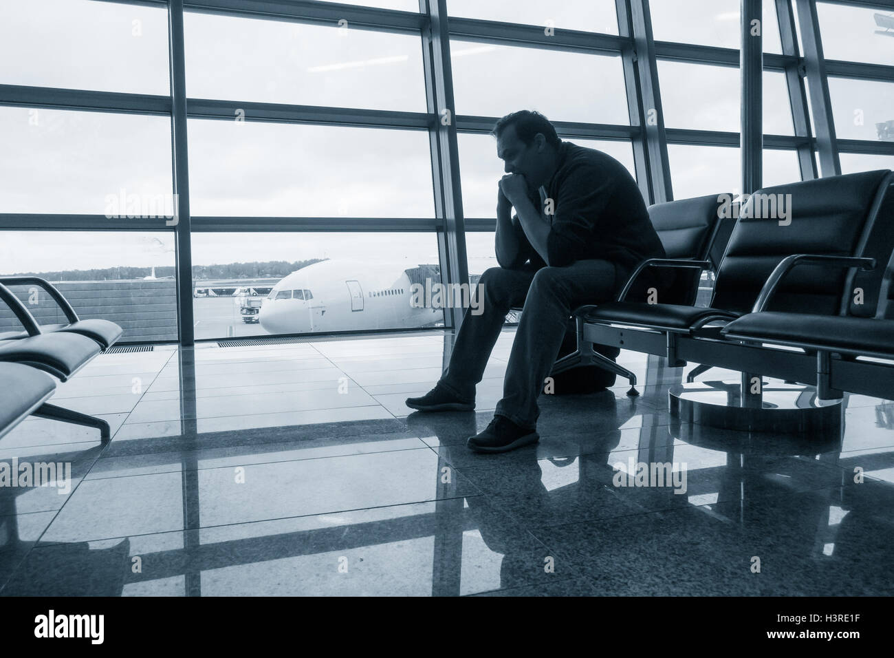 Sad man waiting for delayed flight Stock Photo - Alamy