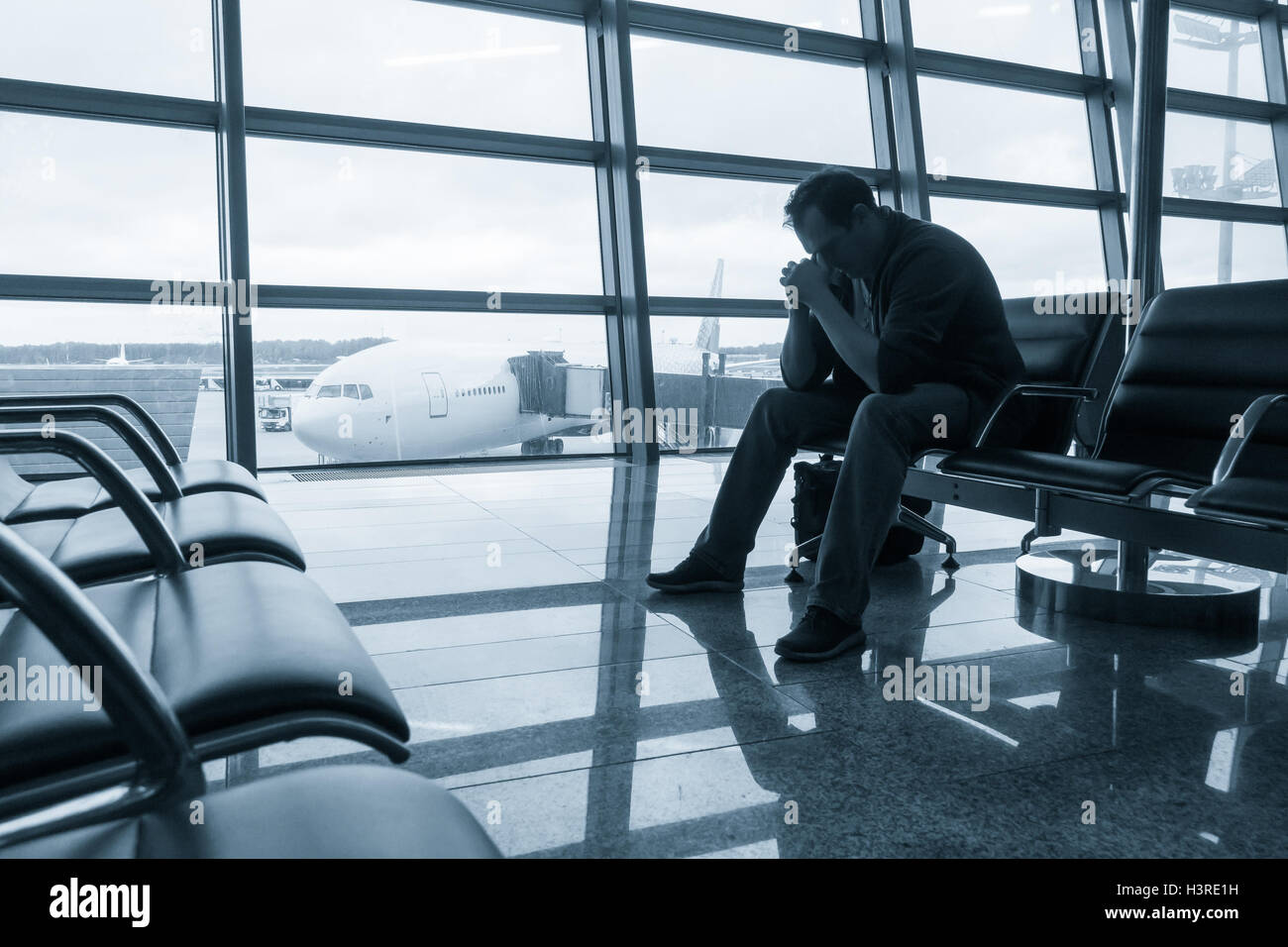 Sad man waiting for delayed flight Stock Photo - Alamy