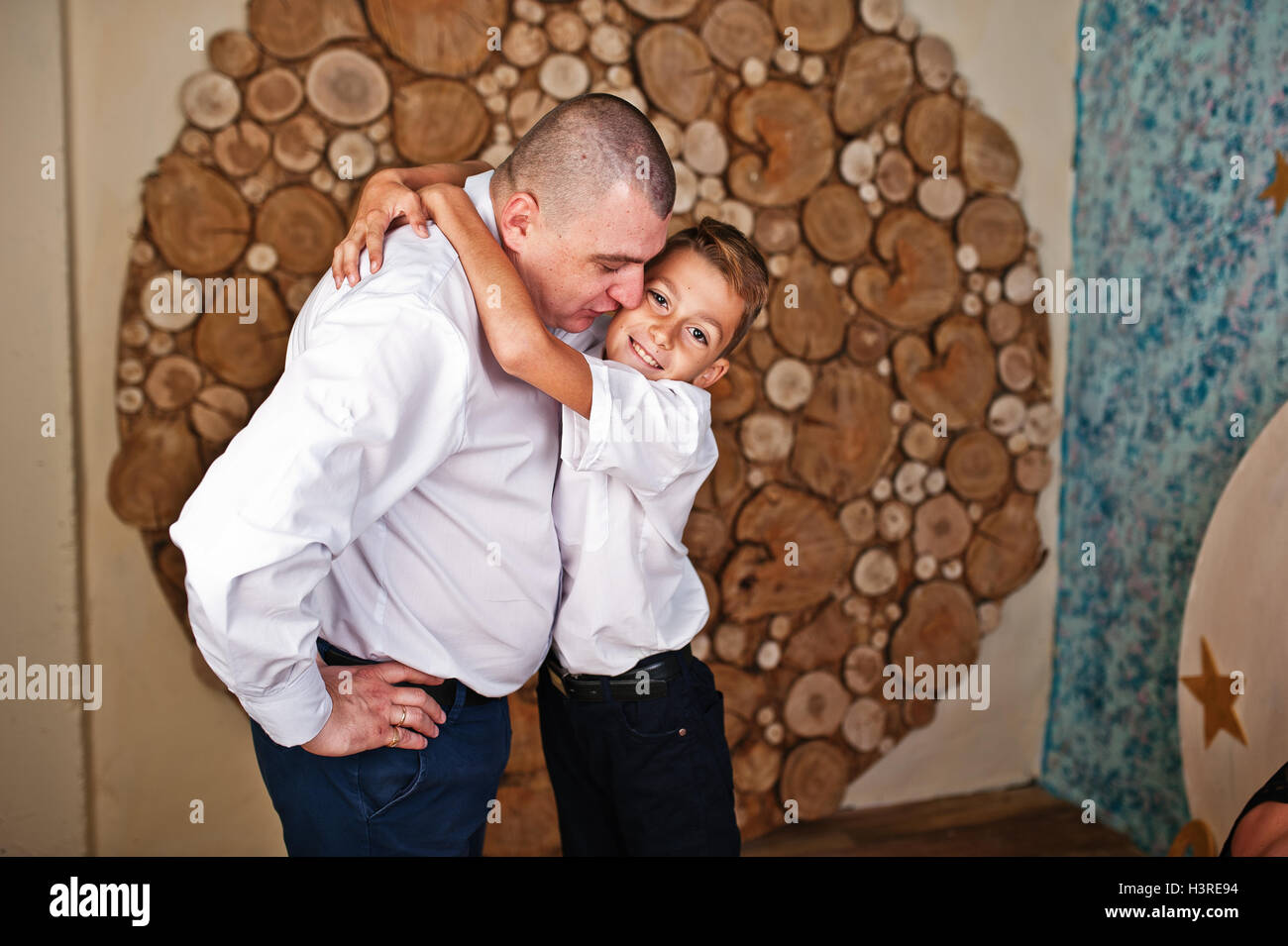 Happy son hugging his father baclground round wooden wall Stock Photo ...