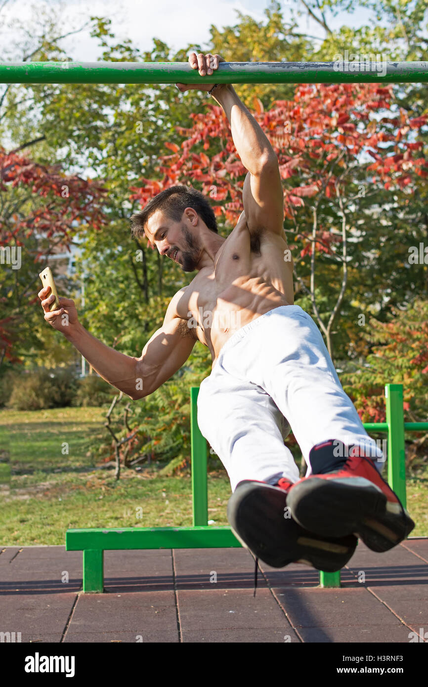 Handsome Male One Arm Pull Up Workout and Smat Phone Using. Street ...