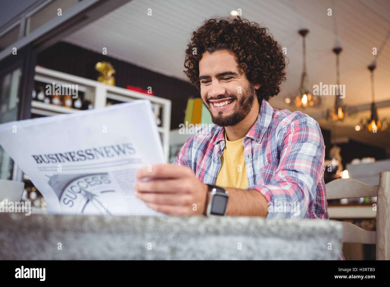 Man smiling while reading newspaper Stock Photo - Alamy
