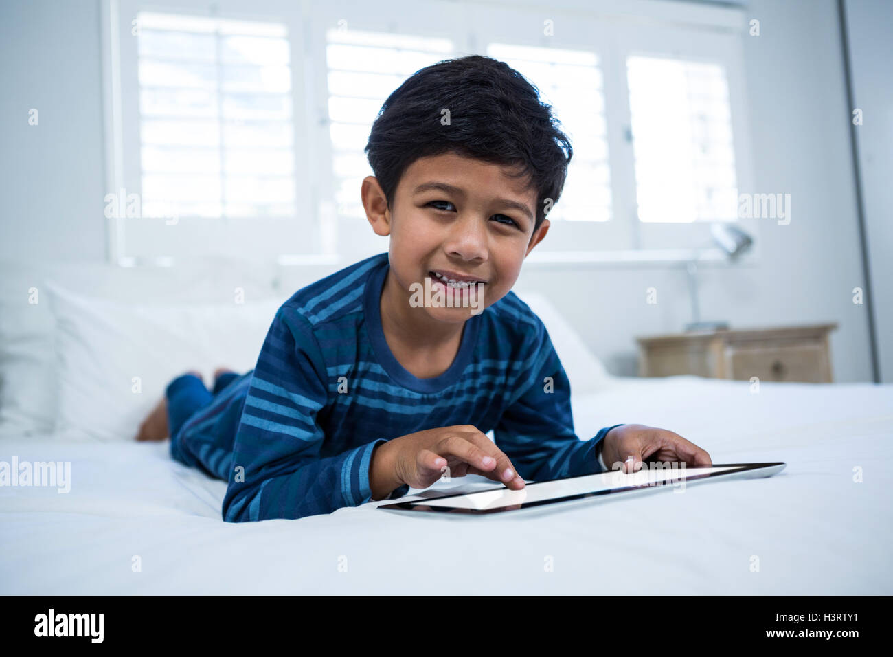 Boy using digital tablet while relaxing on bed Stock Photo - Alamy