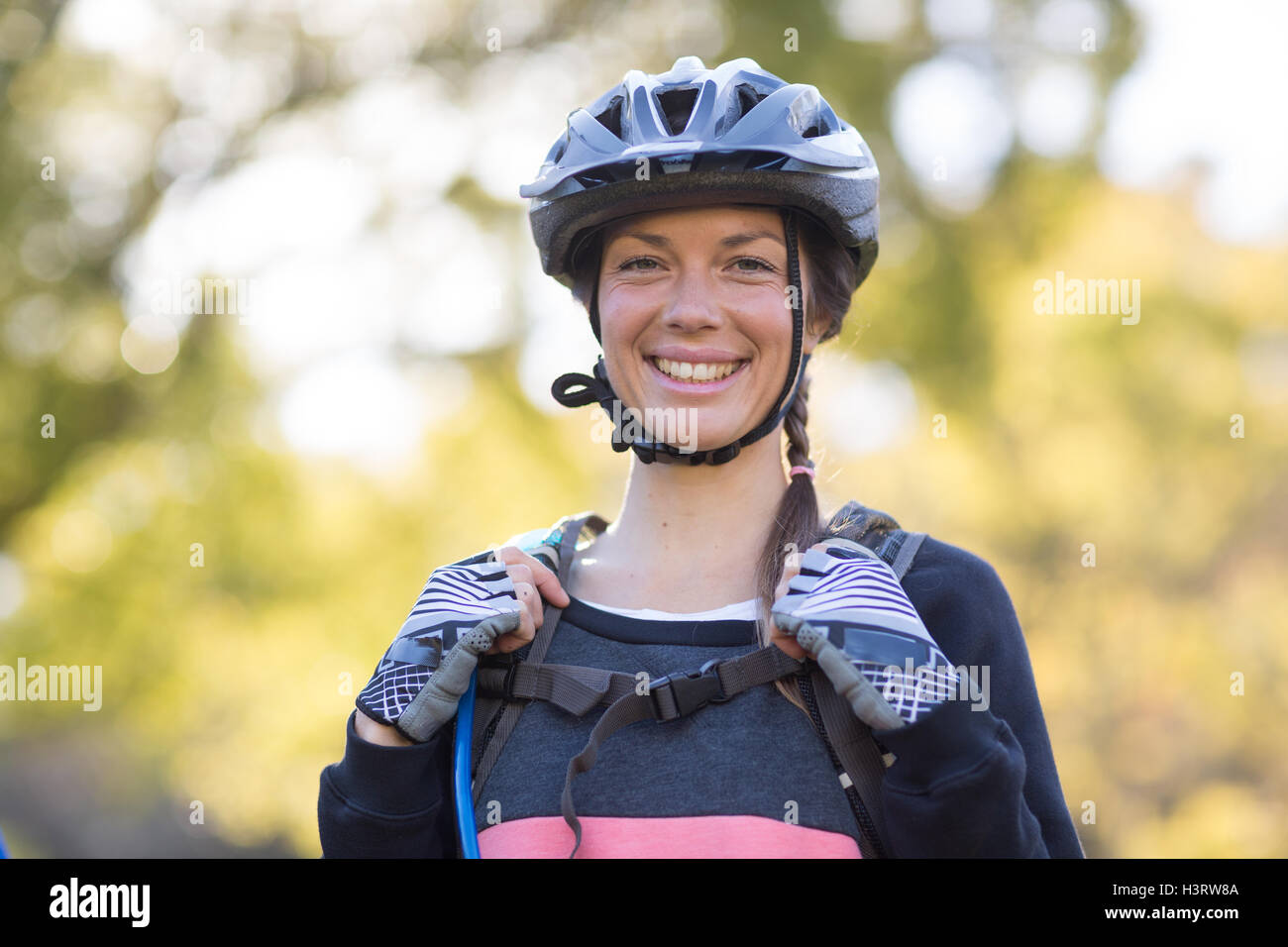 Female biker smiling with backpack Stock Photo - Alamy