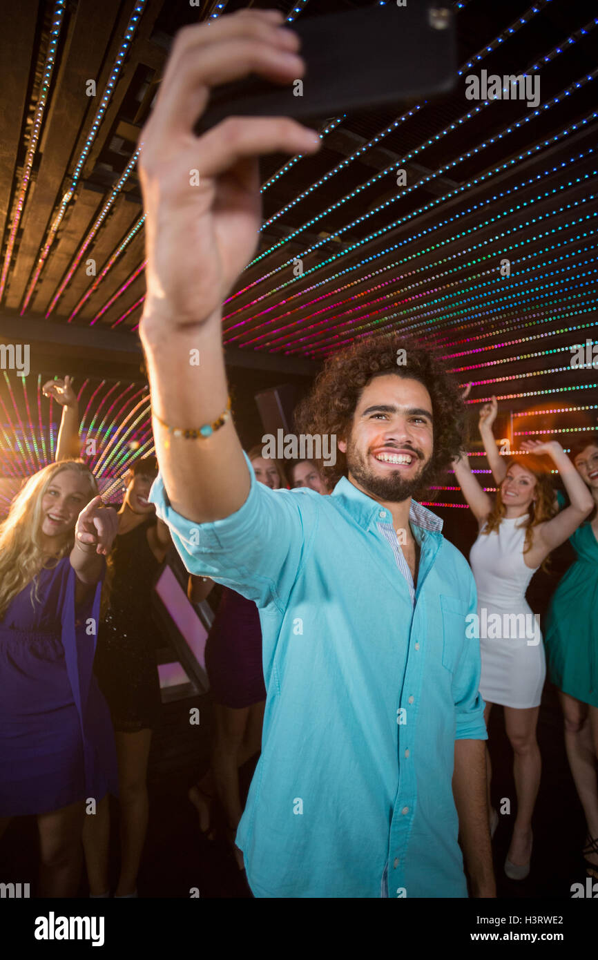 Man taking a selfie from mobile phone while friends dancing on dance ...