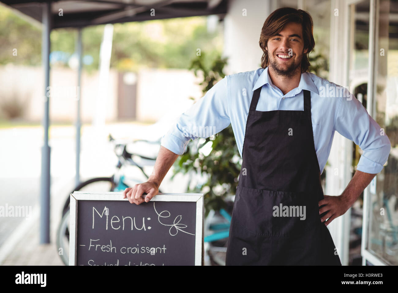 Waiter standing with menu board outside the cafe Stock Photo - Alamy