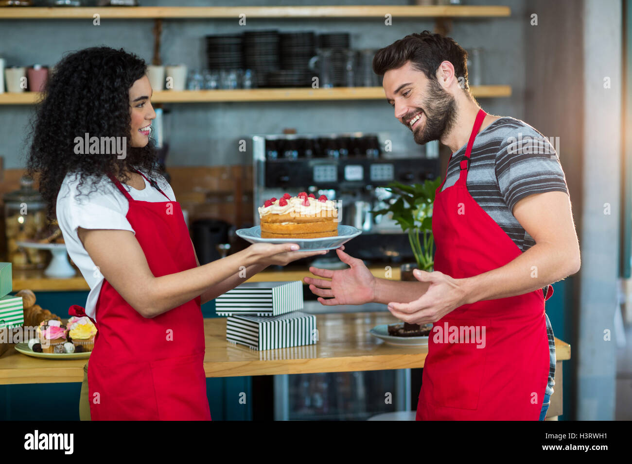 Smiling waitress giving a plate of cake to waiter Stock Photo - Alamy