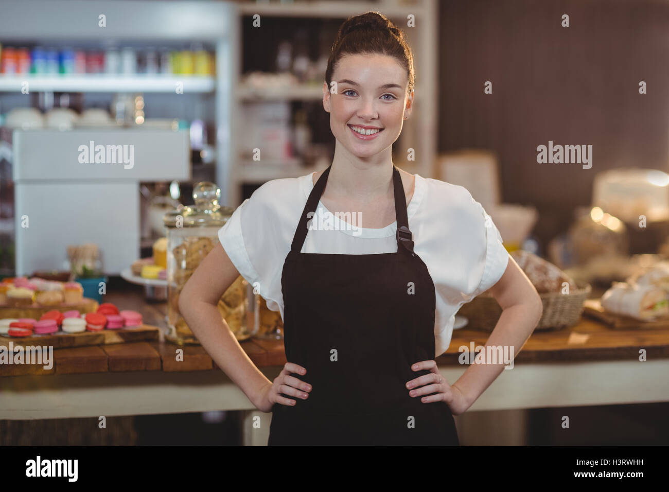 Portrait of smiling waitress standing with hands on hip Stock Photo - Alamy