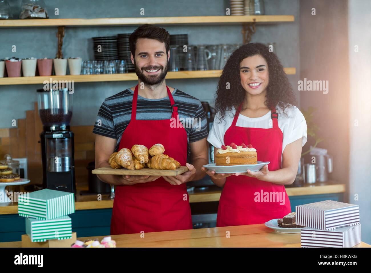 Portrait of waiter and waitress holding a tray of croissants and cake ...