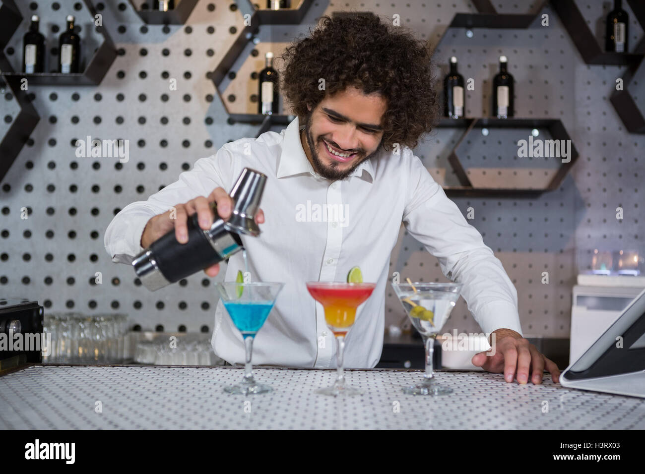 Bartender pouring cocktail into glasses Stock Photo - Alamy