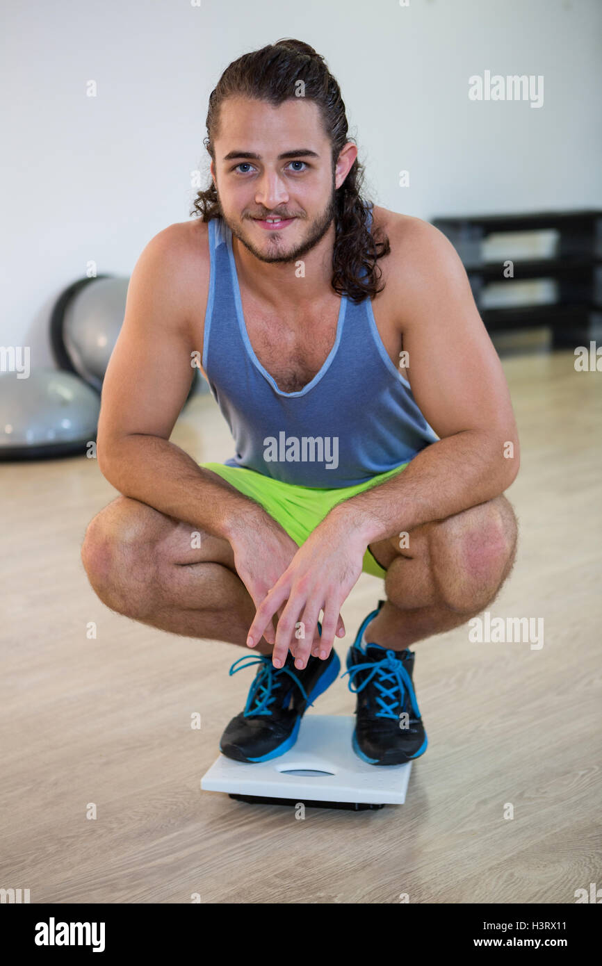 Portrait of smiling man sitting on weight scale Stock Photo - Alamy