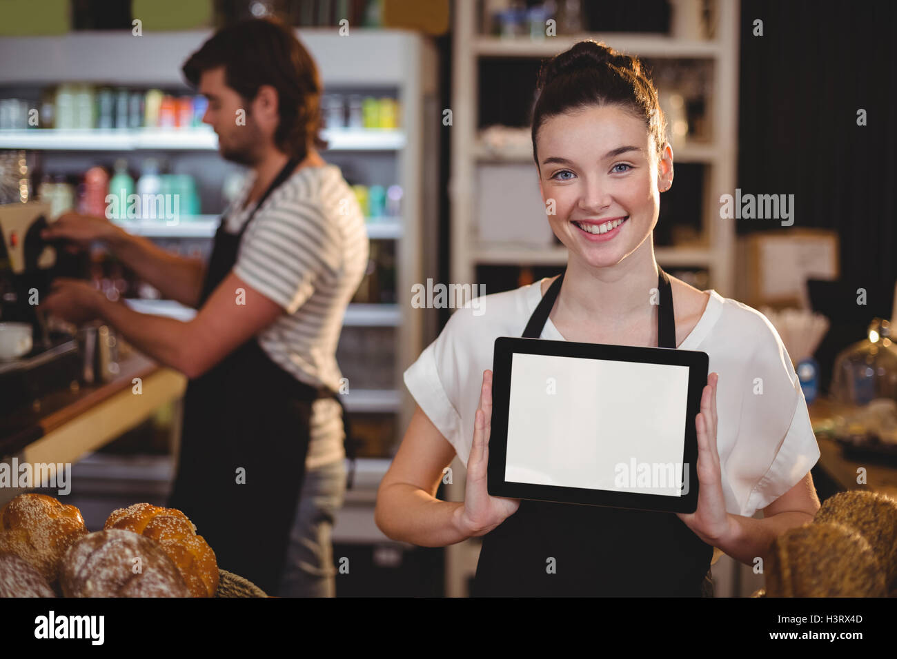 Smiling waitress showing digital tablet Stock Photo - Alamy