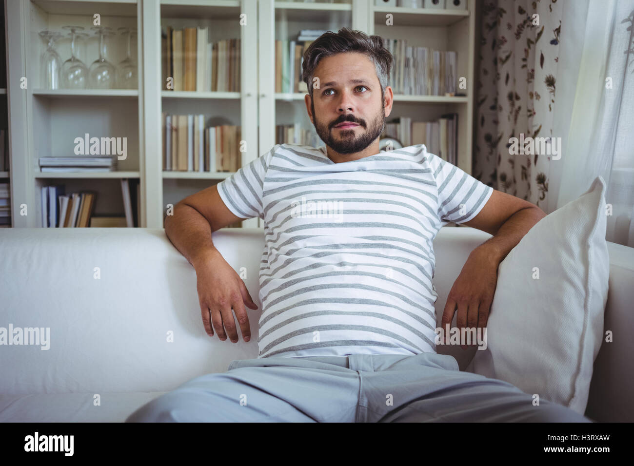 Man sitting on sofa in living room Stock Photo - Alamy