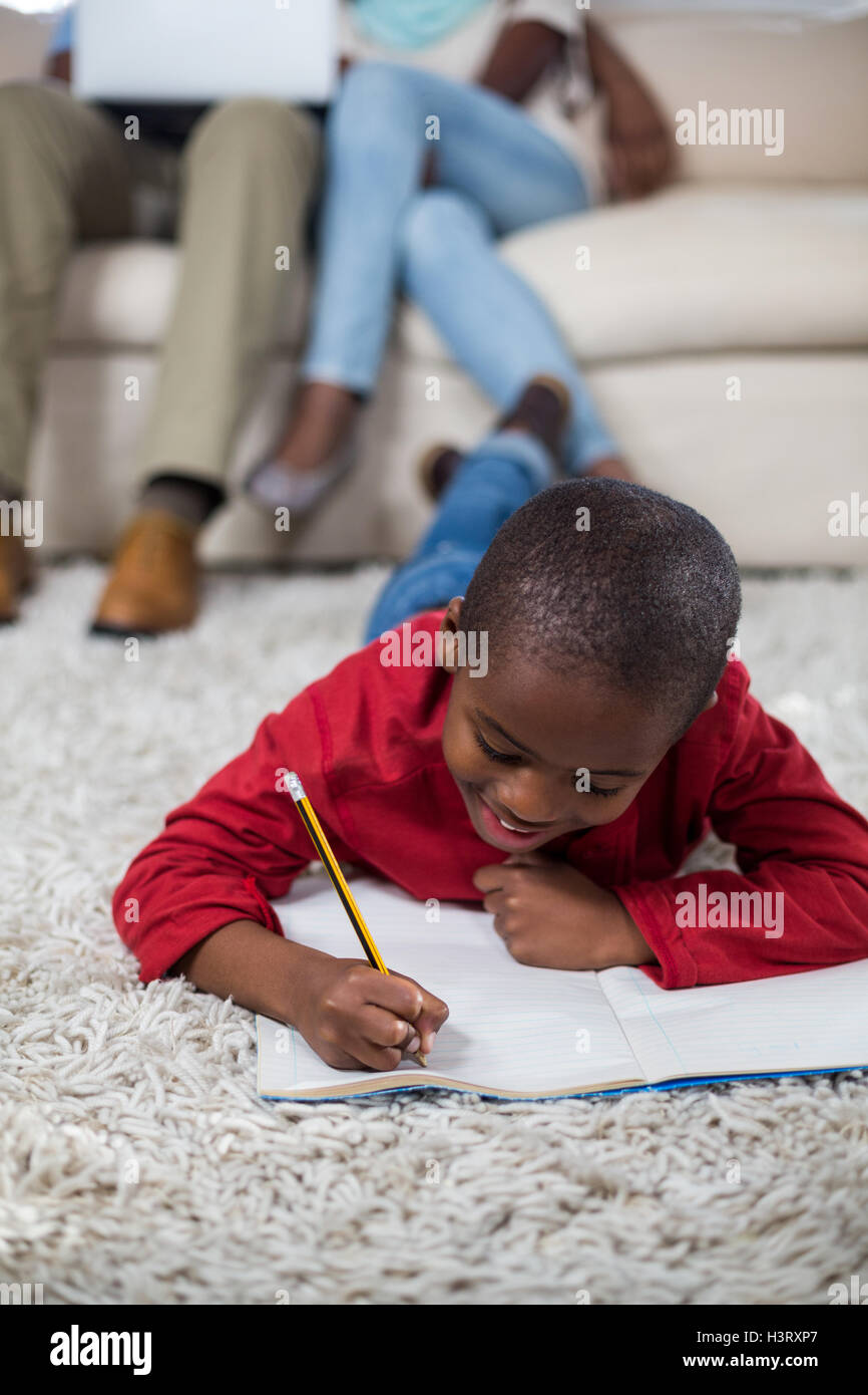 Boy doing homework while lying on the floor Stock Photo - Alamy