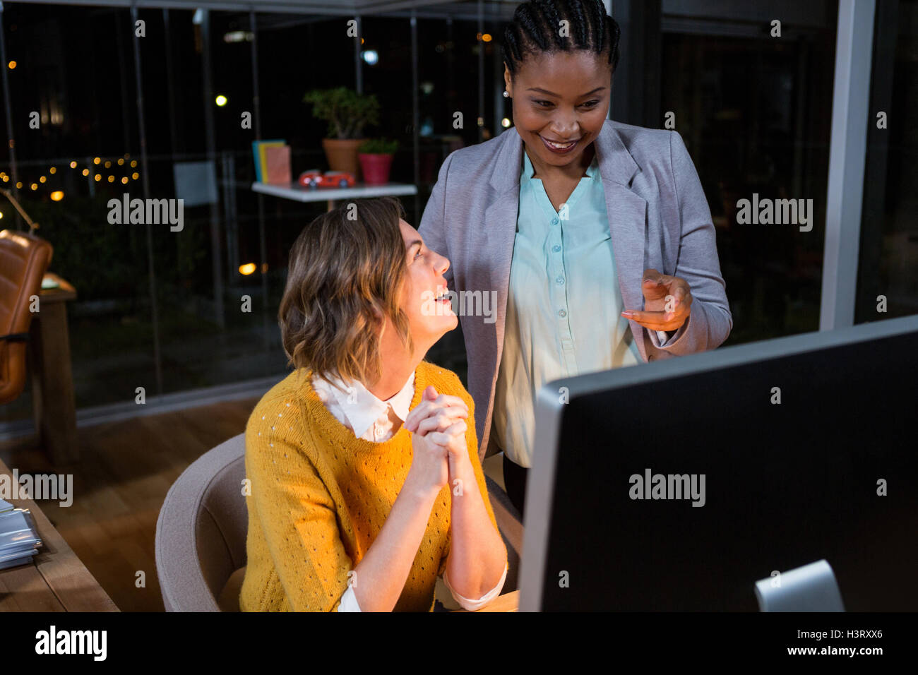 Businesswoman interacting with colleague looking at computer Stock ...