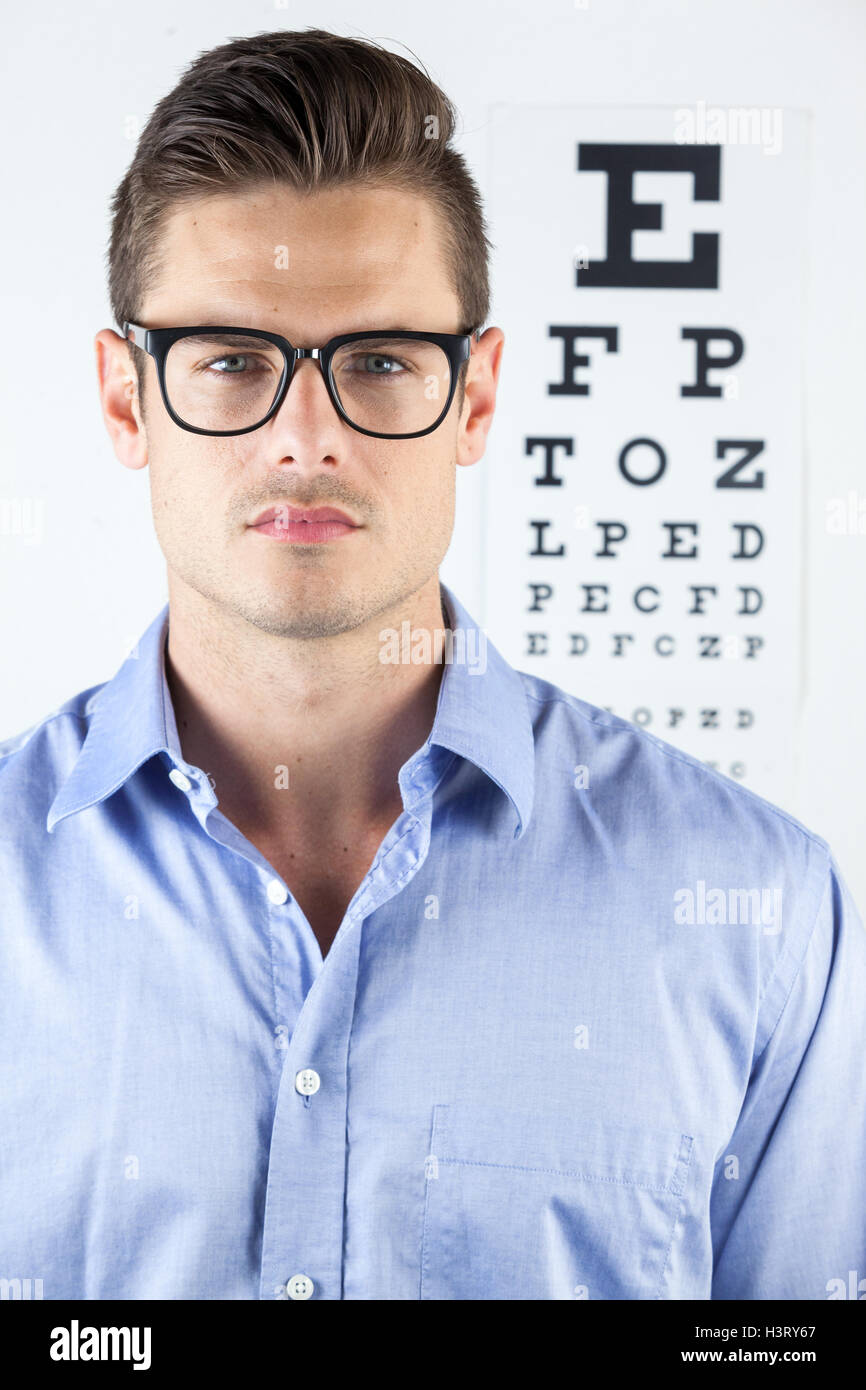 Man wearing spectacles with eye chart in background Stock Photo - Alamy