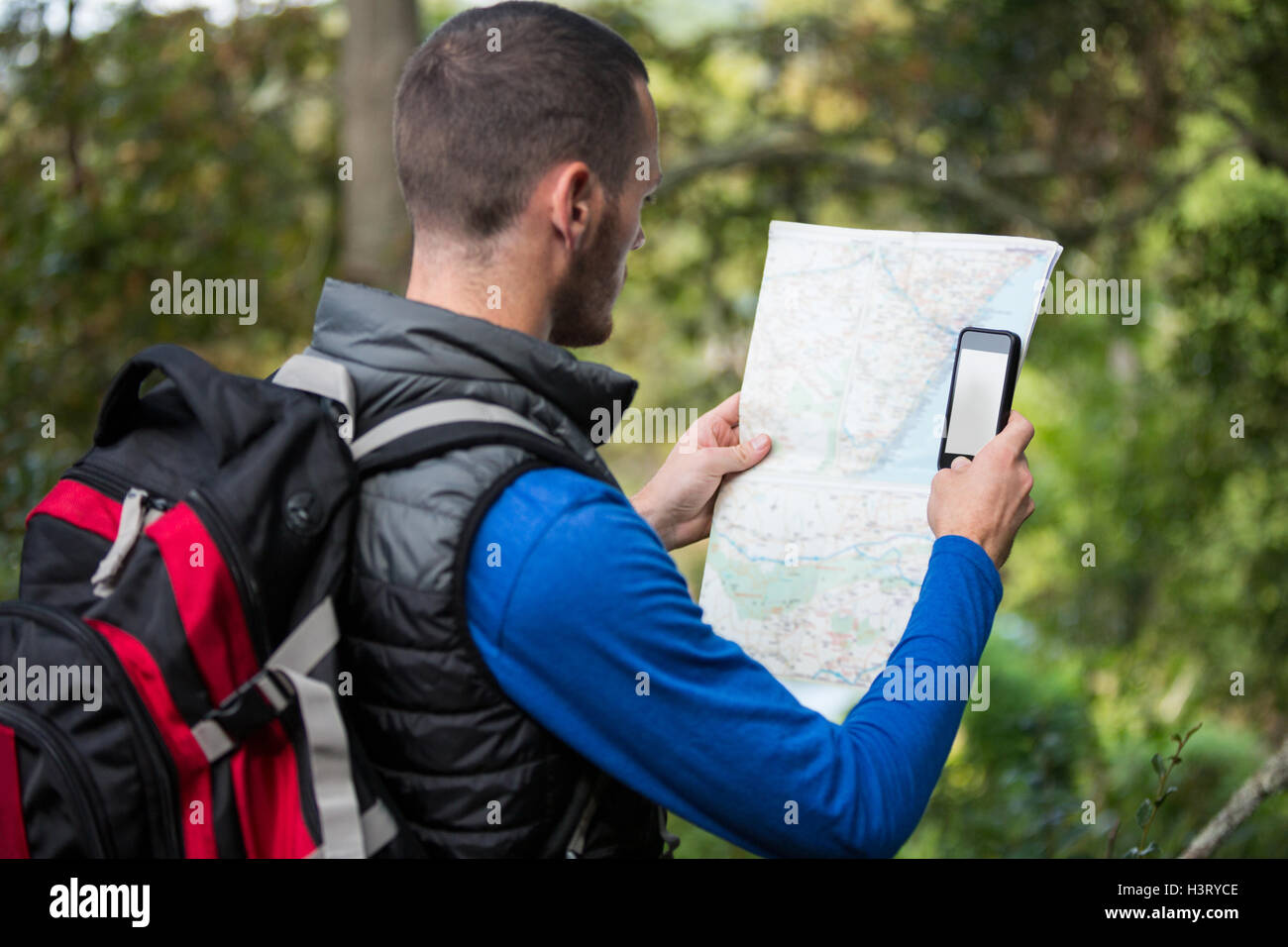 Male hiker looking at map and mobile phone Stock Photo - Alamy