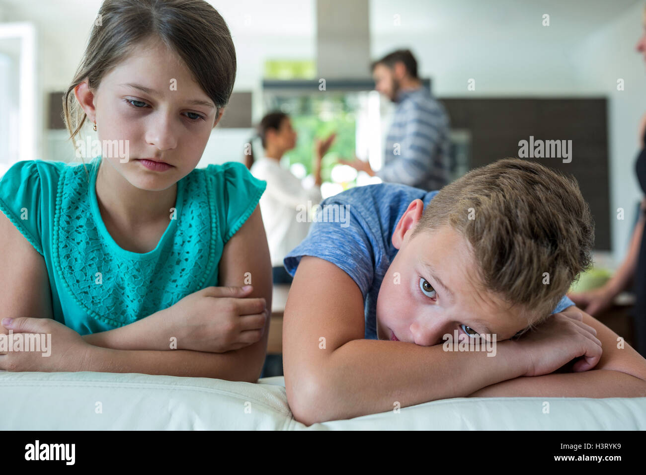 Sad kids leaning on sofa while parents arguing in background Stock ...