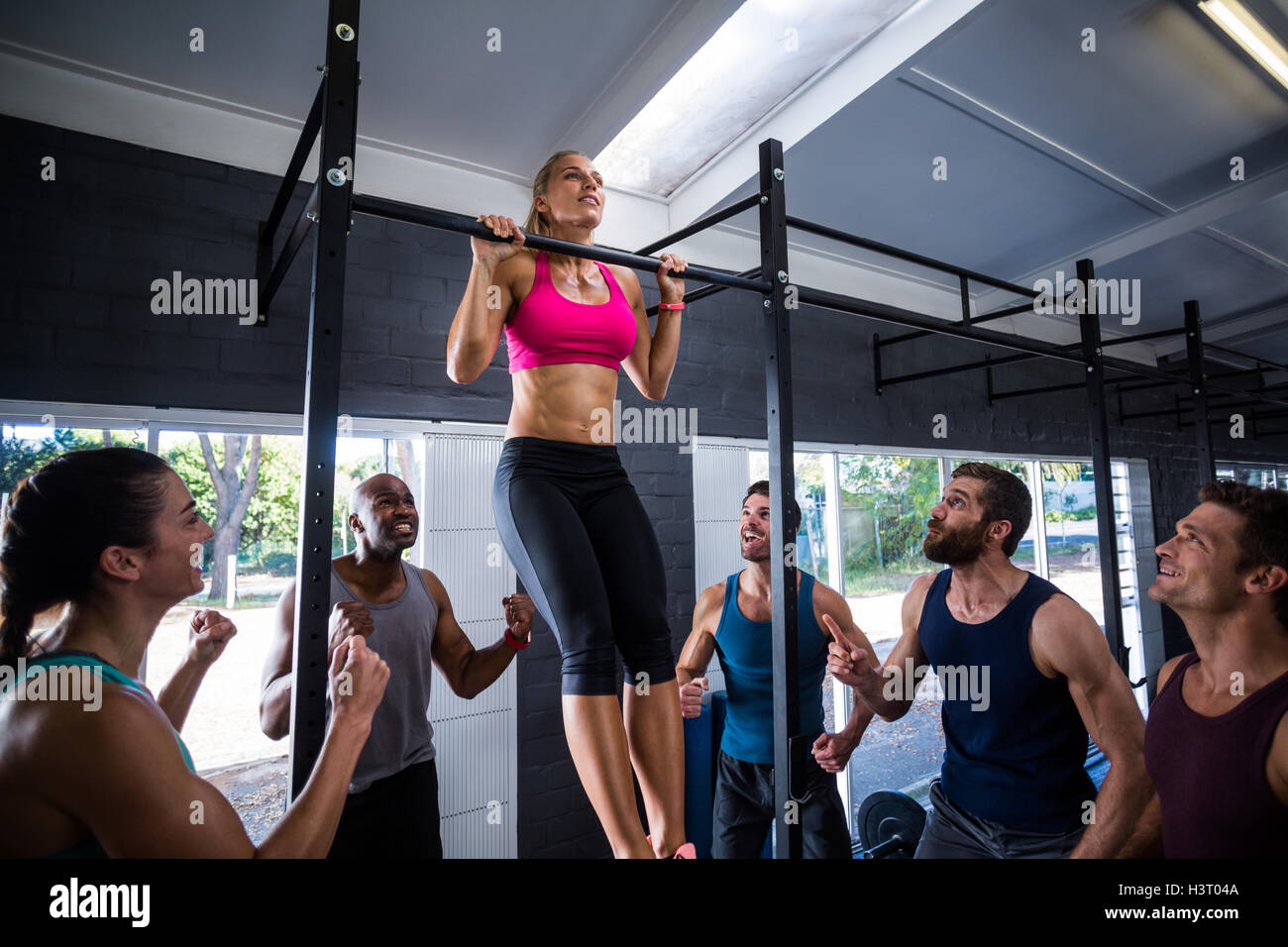 Happy friends cheering woman doing chin-ups Stock Photo - Alamy