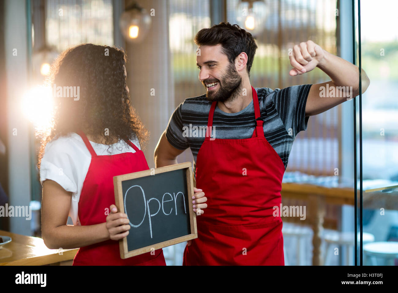Waitress and waiter standing with open sign board in cafe Stock Photo ...