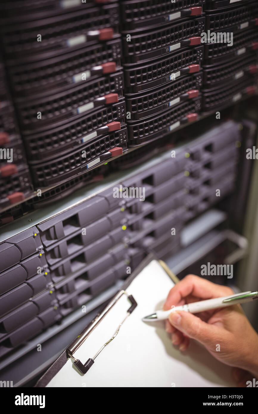 Close-up of technician maintaining record of rack mounted server on ...