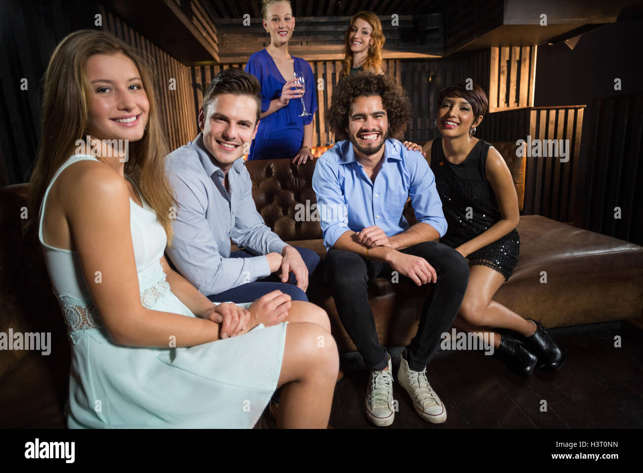 Smiling friends sitting together in sofa Stock Photo - Alamy