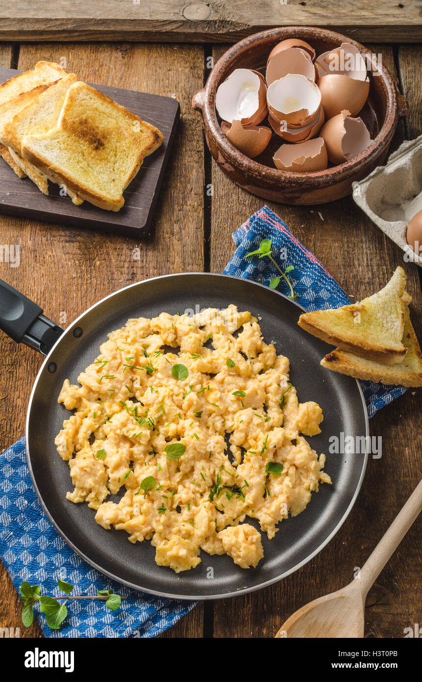 Scrambled eggs rustic style, with toast and herbs Stock Photo - Alamy