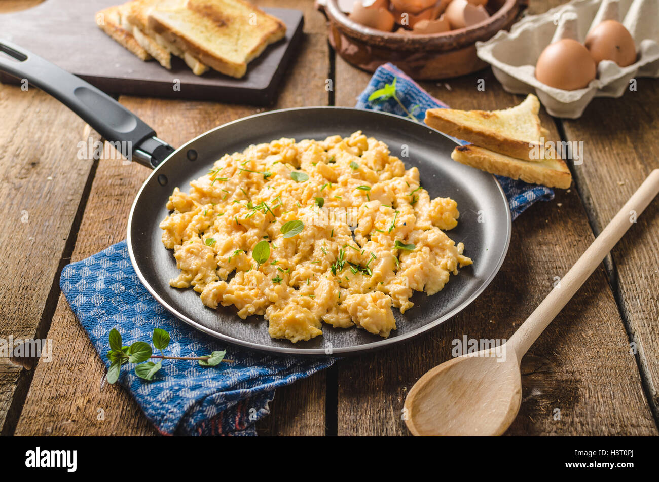 Scrambled eggs rustic style, with toast and herbs Stock Photo - Alamy