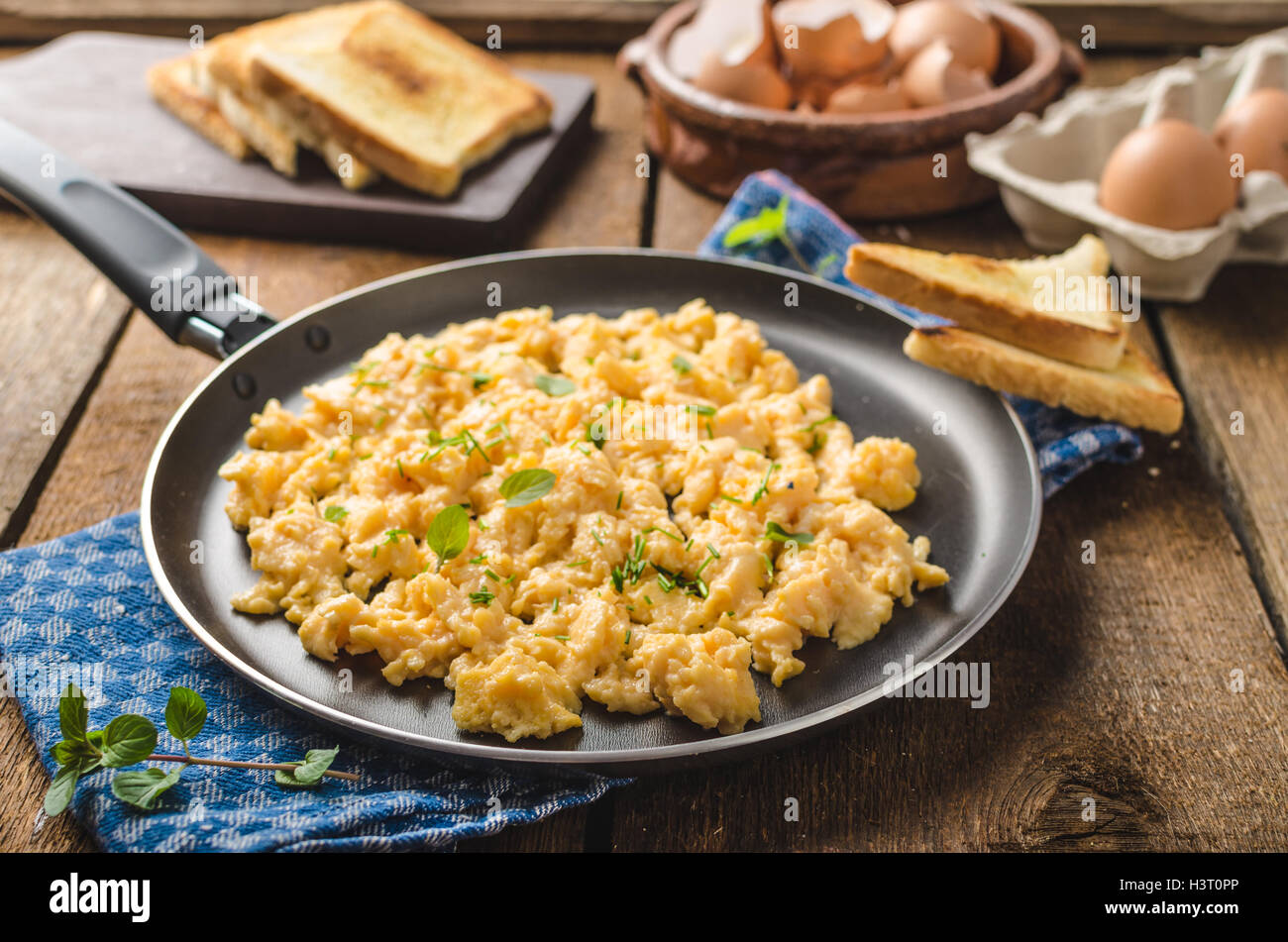 Scrambled eggs rustic style, with toast and herbs Stock Photo - Alamy