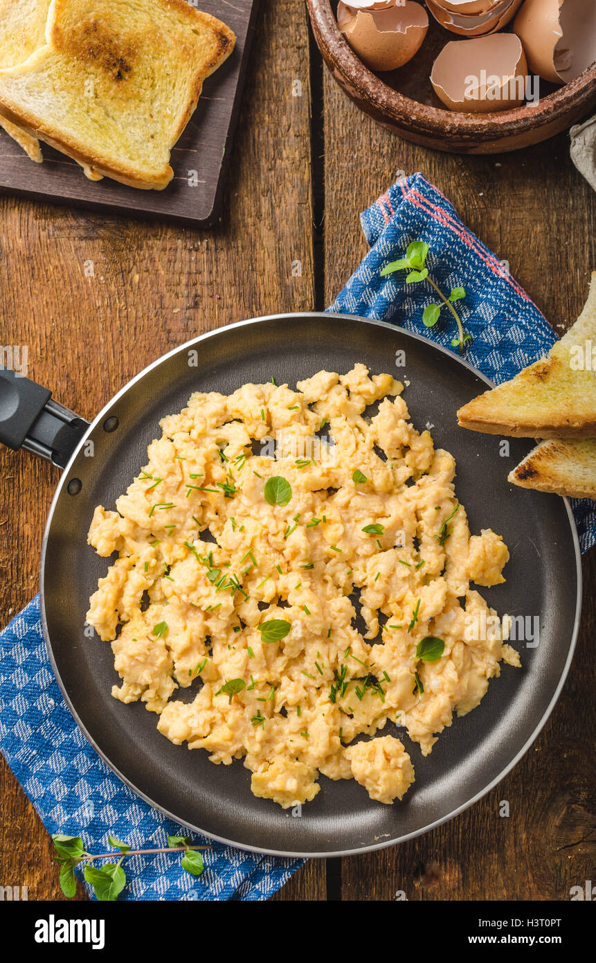 Scrambled eggs rustic style, with toast and herbs Stock Photo - Alamy