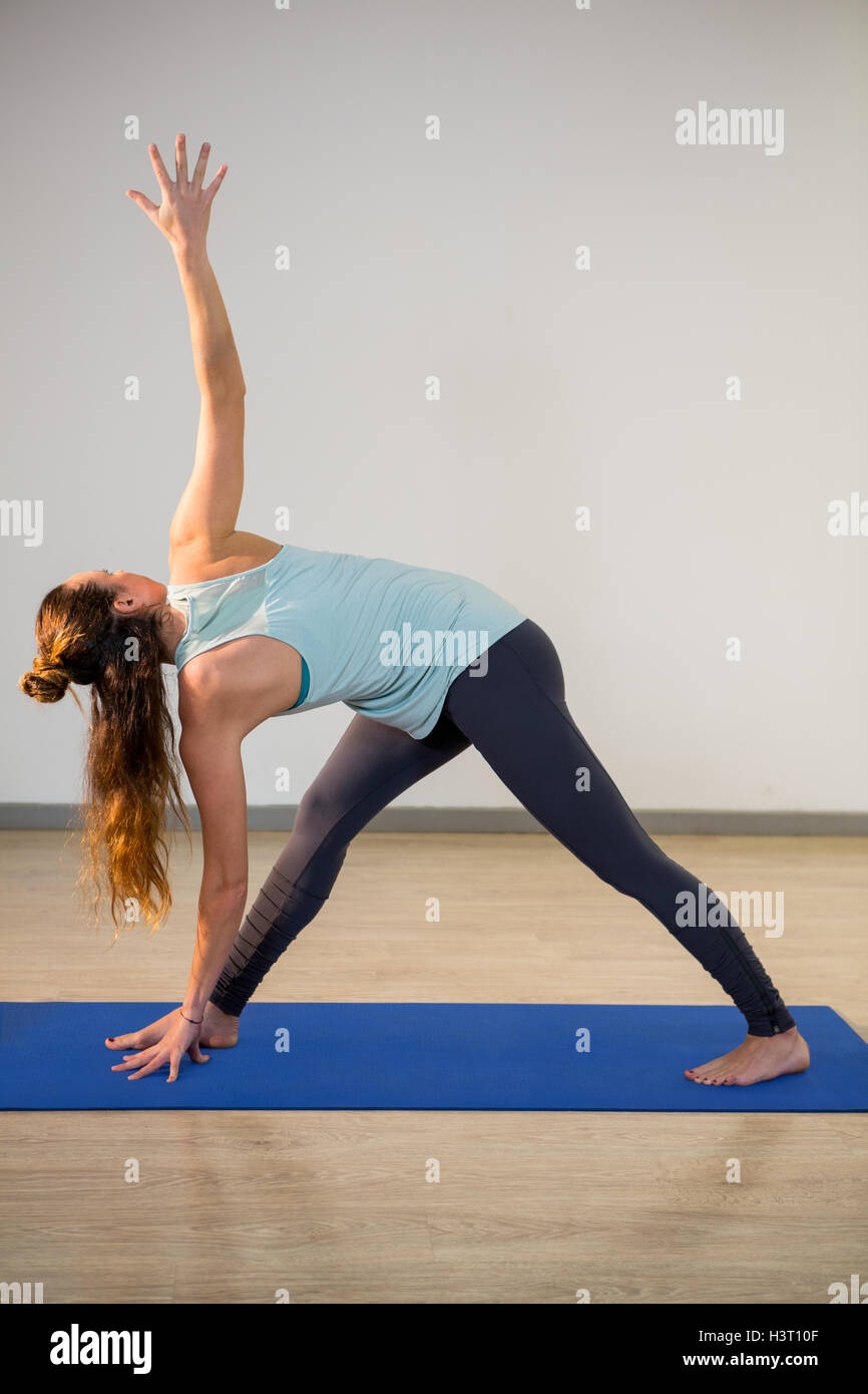 Woman performing triangle pose on exercise mat Stock Photo - Alamy